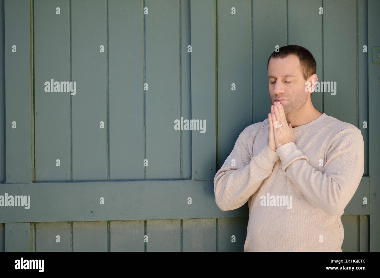 Man praying outdoors in front of a green wooden background Stock Photo ...
