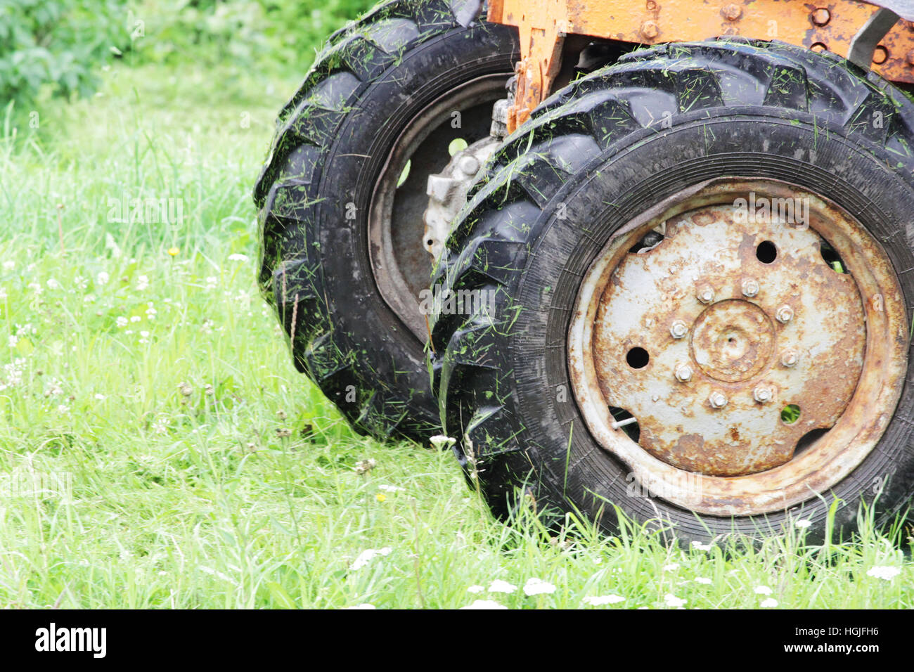 Old work tractor wheel who mows the grass on the field in summer Stock ...
