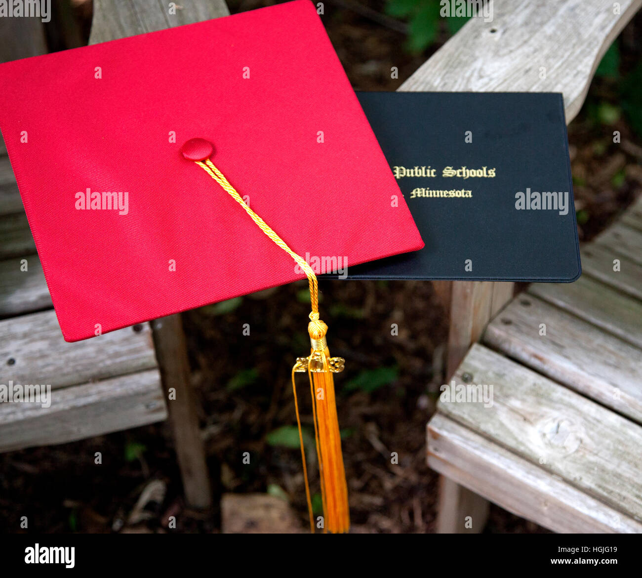 High school graduates red cap with gold tassel and diploma folder ...