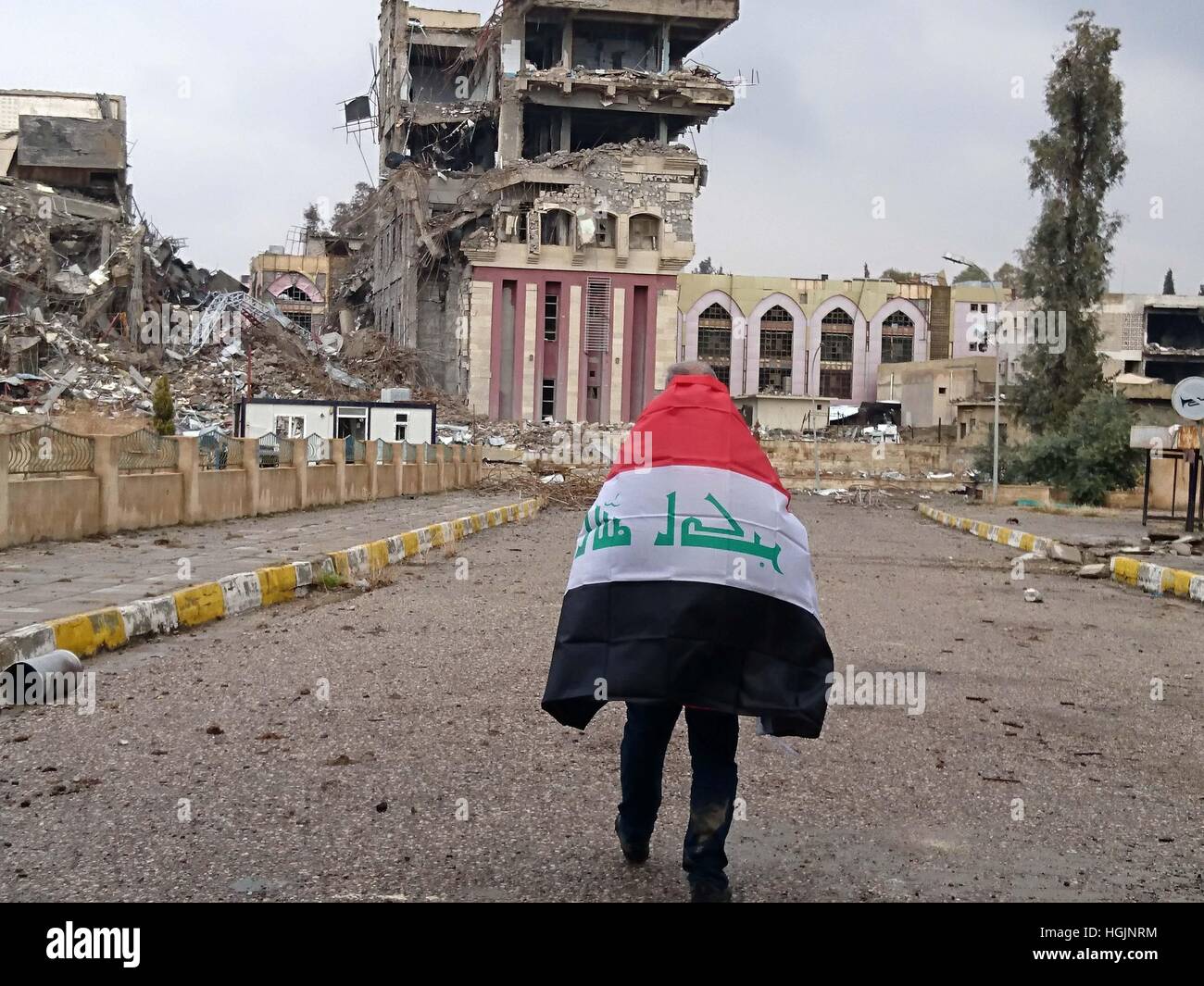 Baghdad, Iraq. 22nd Jan, 2017. A man wearing Iraqi flag walks past the ...