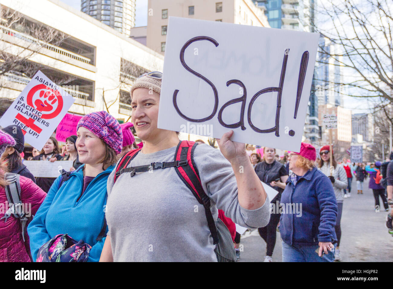 A woman marches on the street holding a handmade sign saying "Sad ...