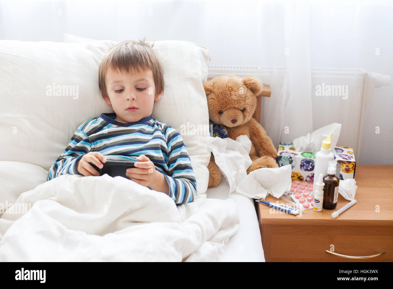 Sick child boy lying in bed with a fever, resting at home Stock Photo ...