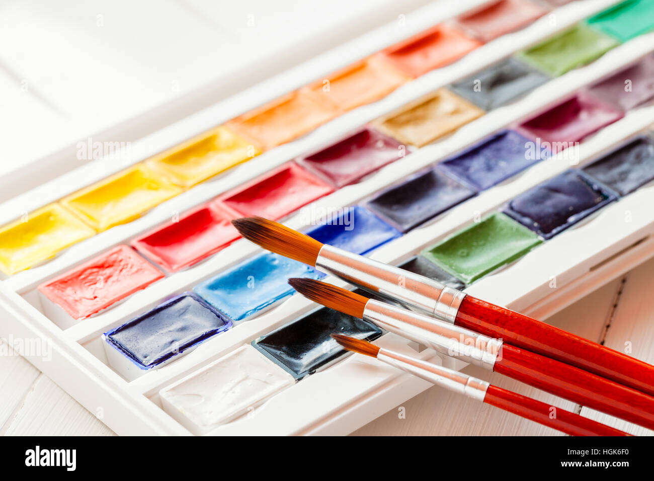 Brushes for water color painting and set of watercolor paints on table ...