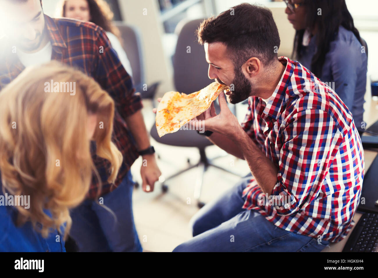 Coworkers eating pizza during work break at office Stock Photo - Alamy