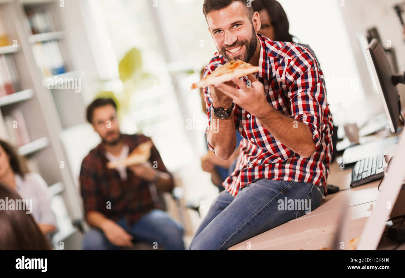 Coworkers eating pizza during work break at office Stock Photo - Alamy