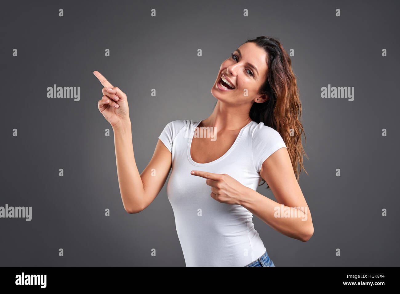 A beautiful young woman smiling and pointing sideways Stock Photo - Alamy