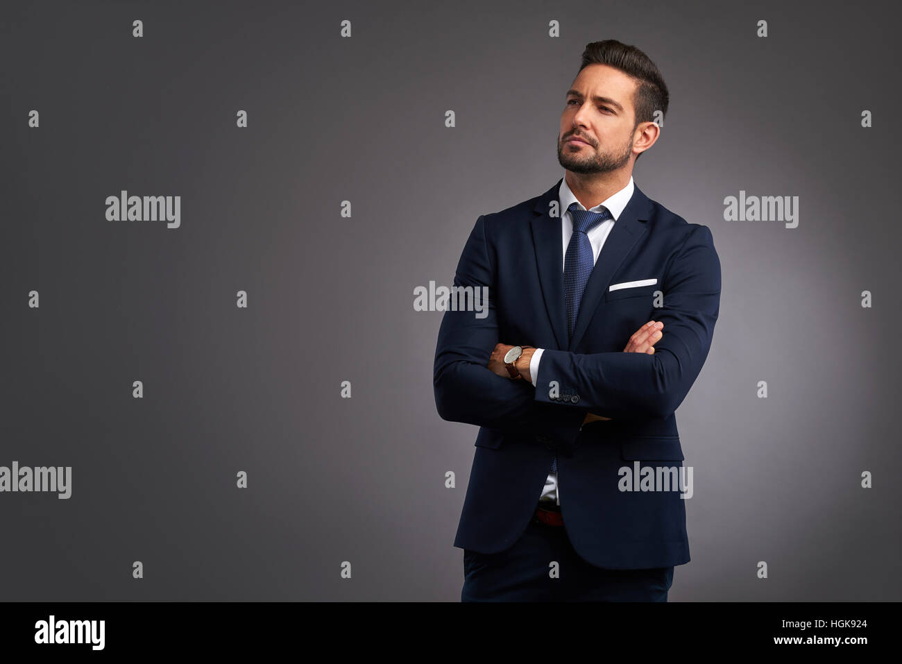 A confident elegant handsome young man standing in front of a grey ...