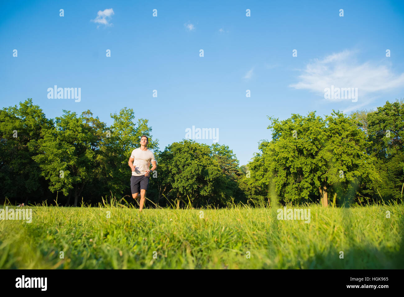 A handsome young man running on a summer evening in the sunset in a ...