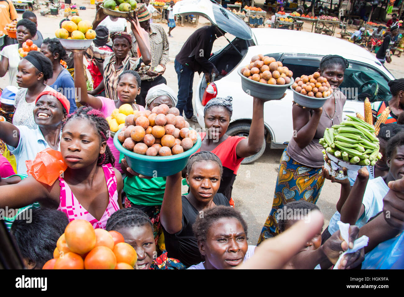 Fruit and vegetable hawkers selling fruit to a stopped bus in Zambia ...