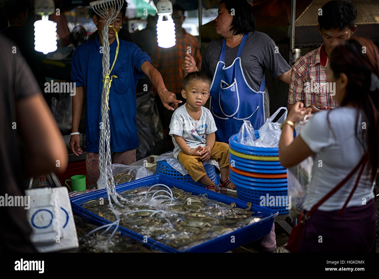 Child bored. Boy sat at his family's fresh fish market stall and ...