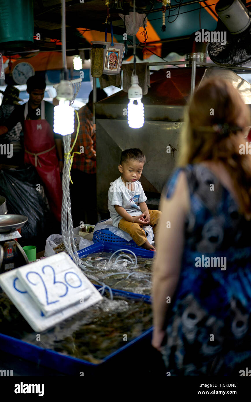 Child bored. Boy sat at his family's fresh fish market stall and ...