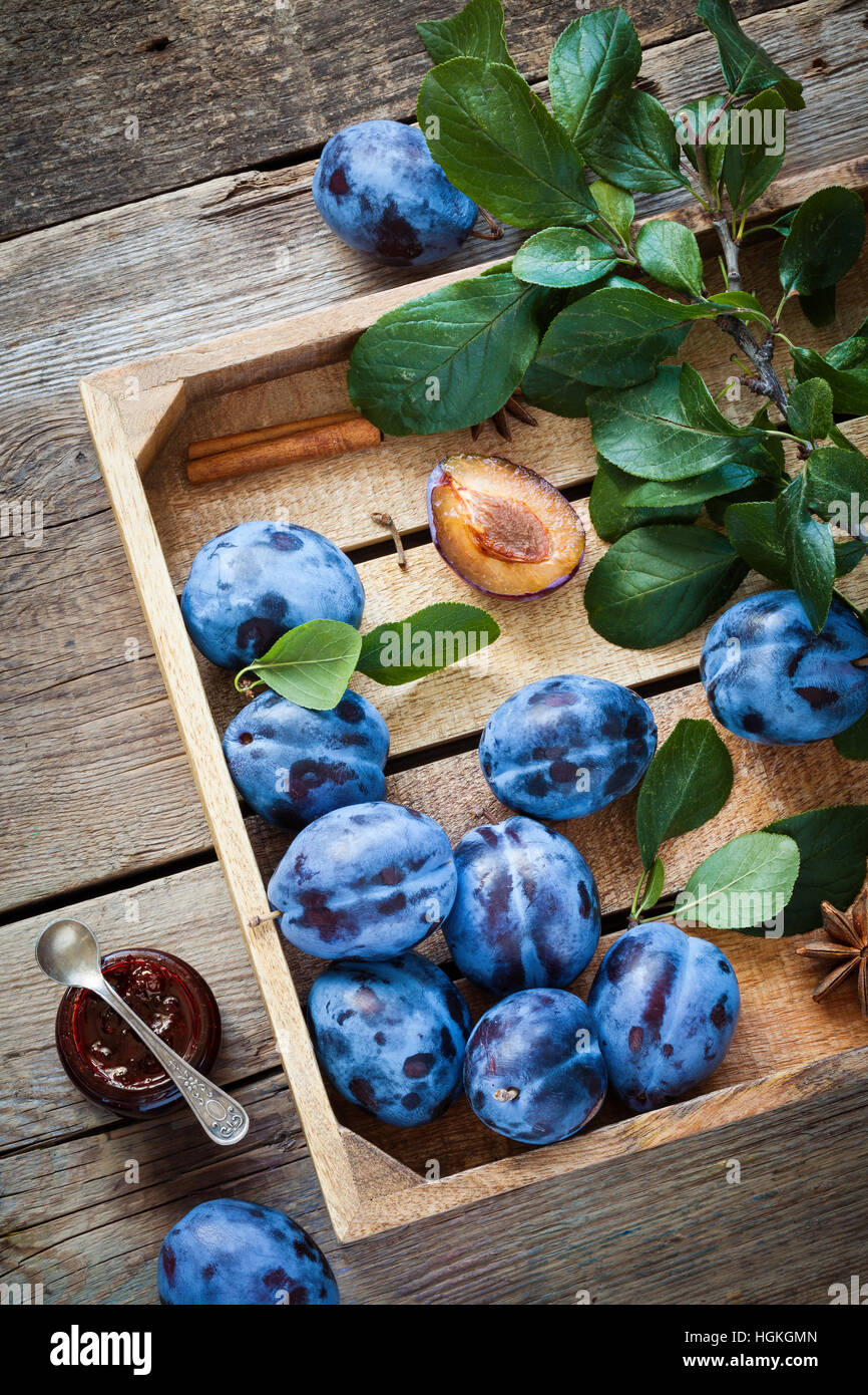 Fresh plums in wooden box and jar of fruit jam. Top view, flat lay ...