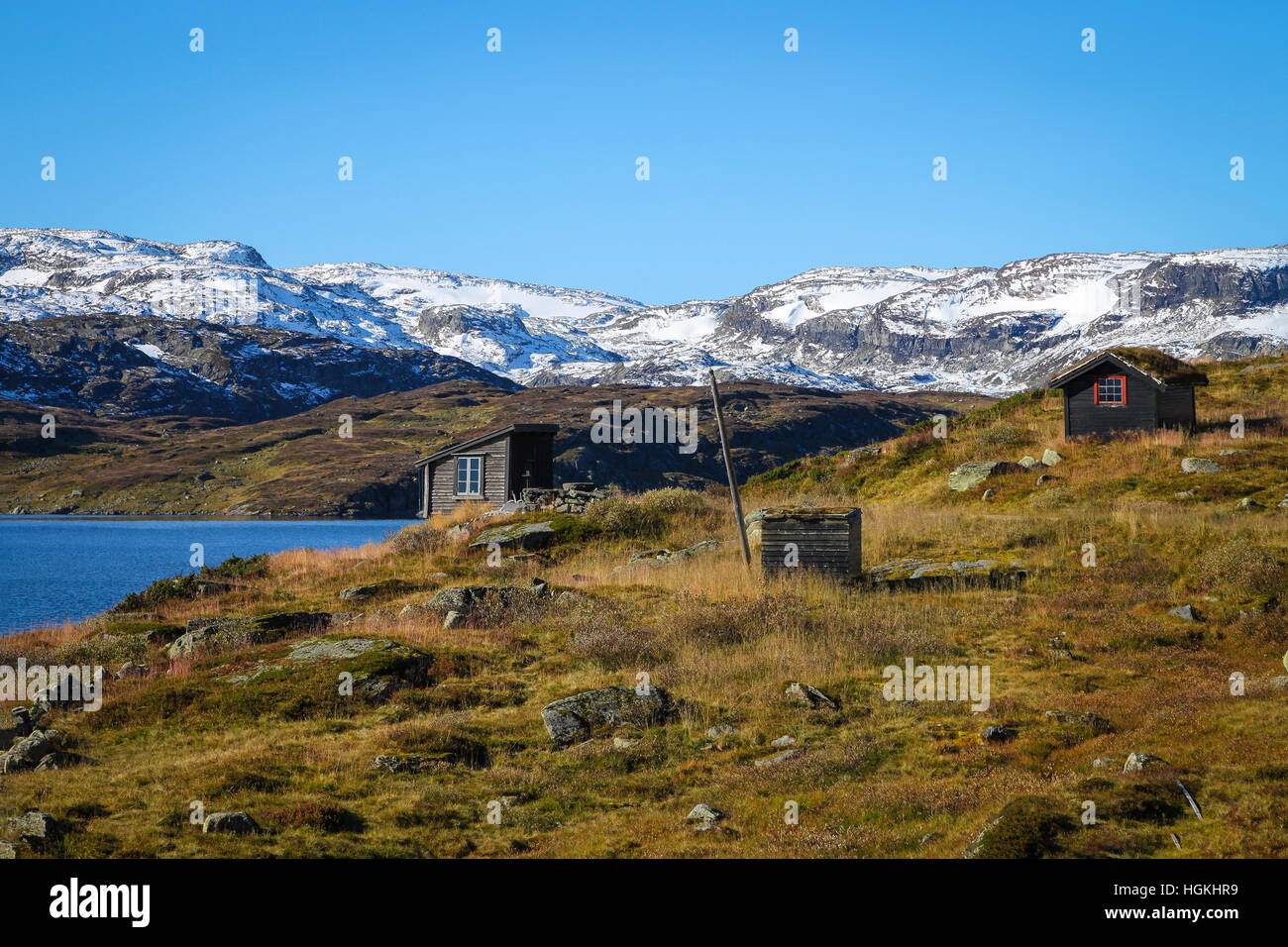Lake with snow covered mountains and grass roofed shacks in the ...