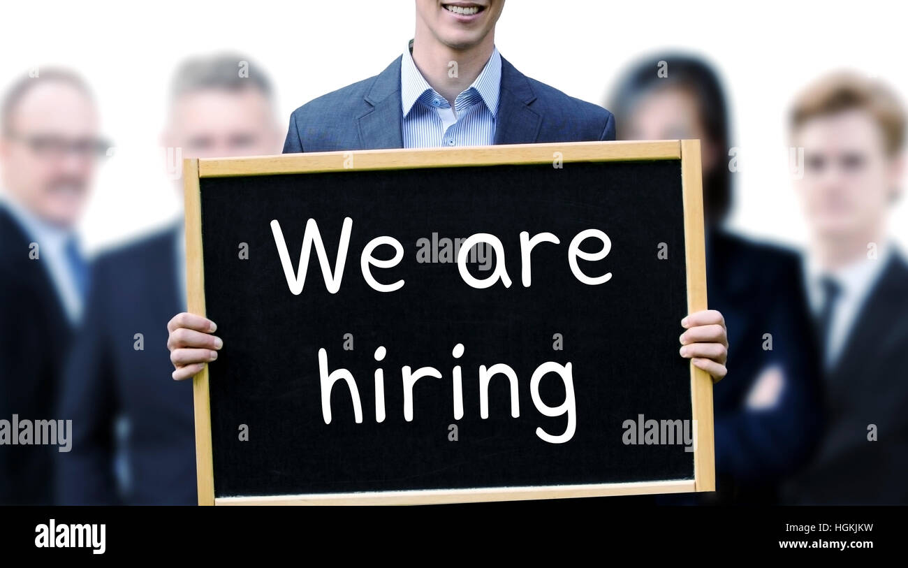 young businessman holding a sign with the words We Are Hiring and group ...