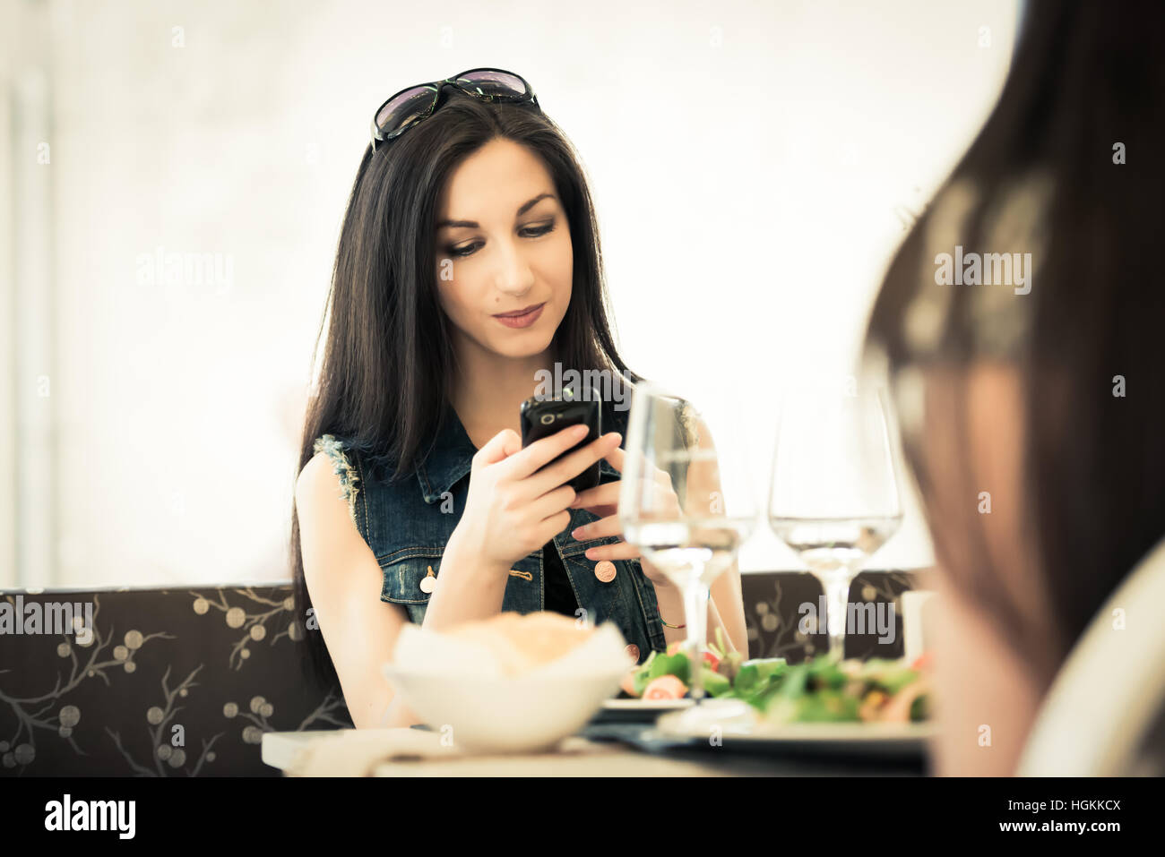 Female friends at the restaurant using mobile phone Stock Photo - Alamy