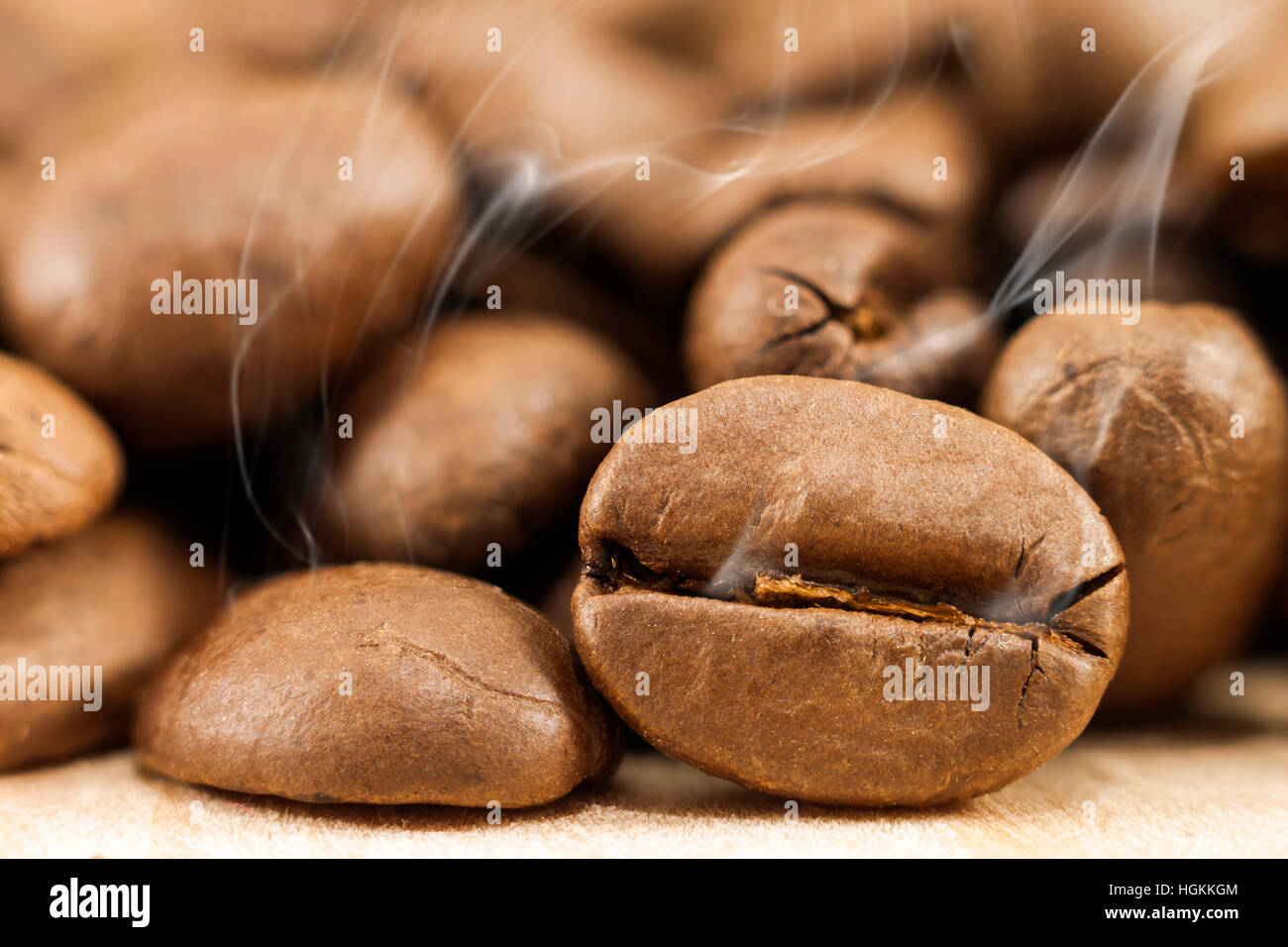 Brown coffee beans with white smoke vapour on yellow textured wooden ...