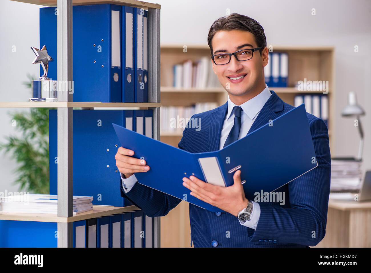 Young man standing next to the shelf with folders Stock Photo - Alamy