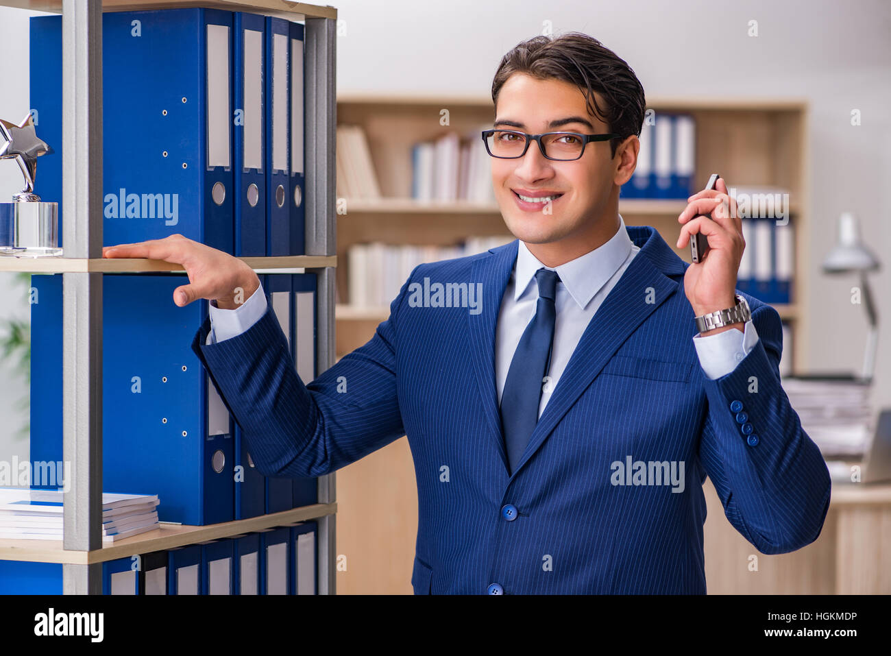 Young man standing next to the shelf with folders Stock Photo - Alamy