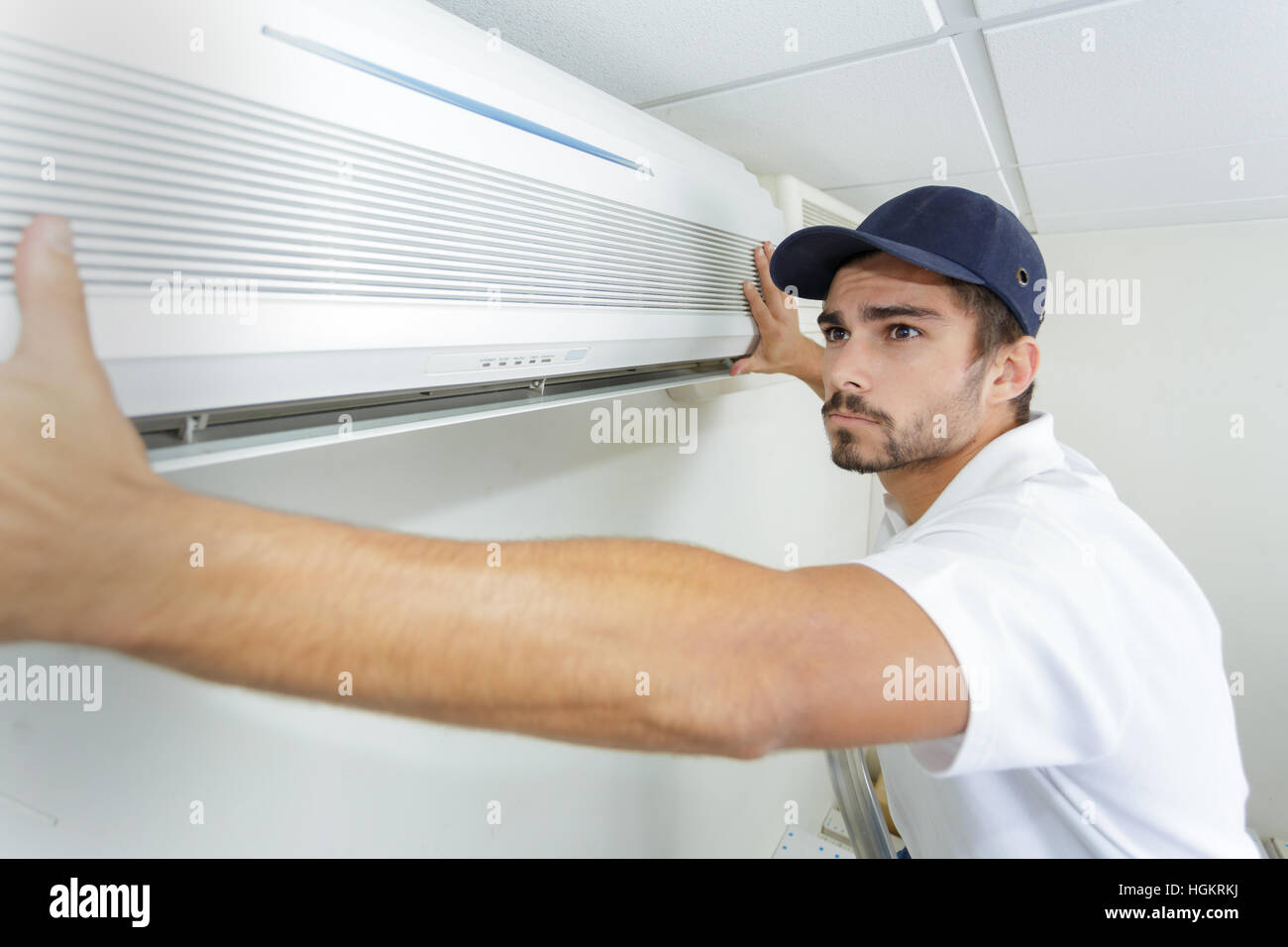 tech guy carefully installing new ac Stock Photo - Alamy