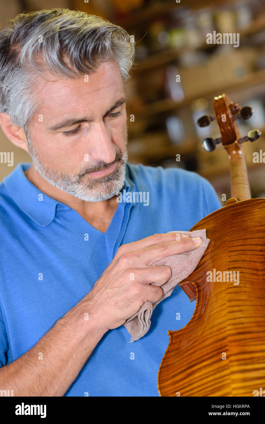 Man polishing string instrument Stock Photo - Alamy