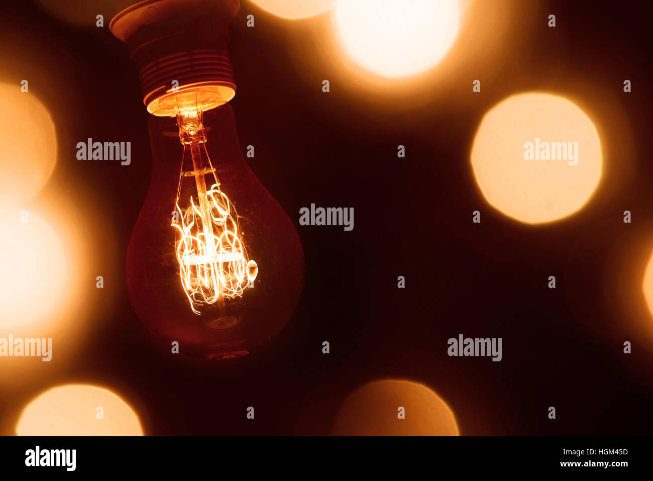 lighted vintage incandescent bulb on dark orange blurred background ...