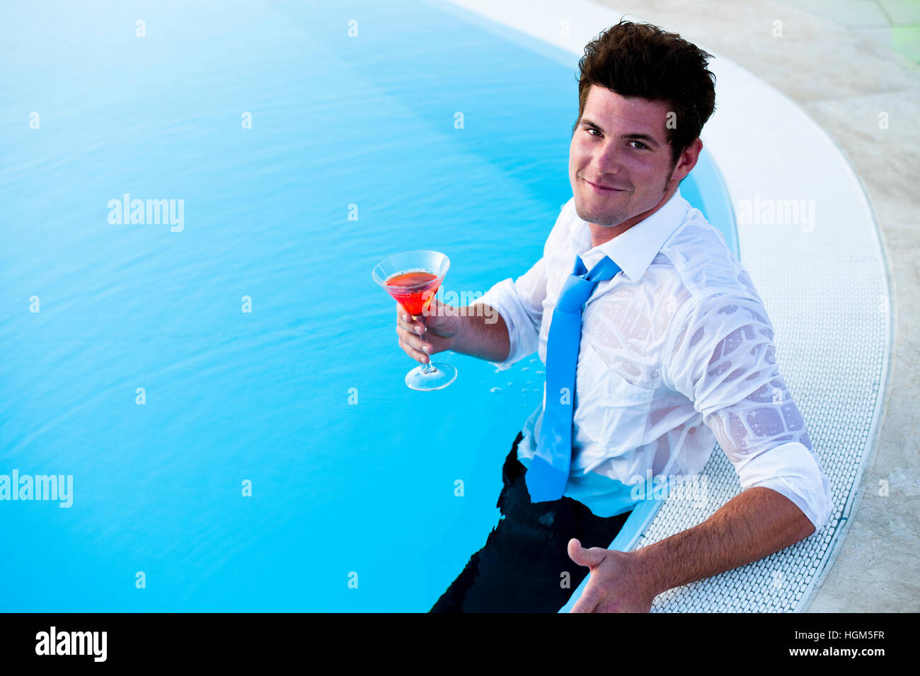 Young man having a drink in the pool Stock Photo - Alamy