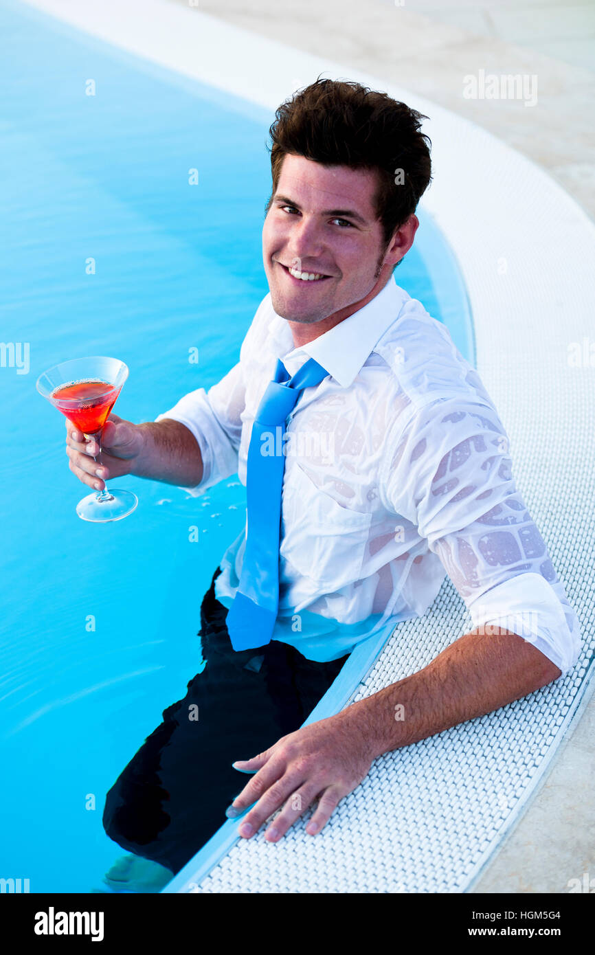 Attractive young man in the pool having a drink Stock Photo - Alamy
