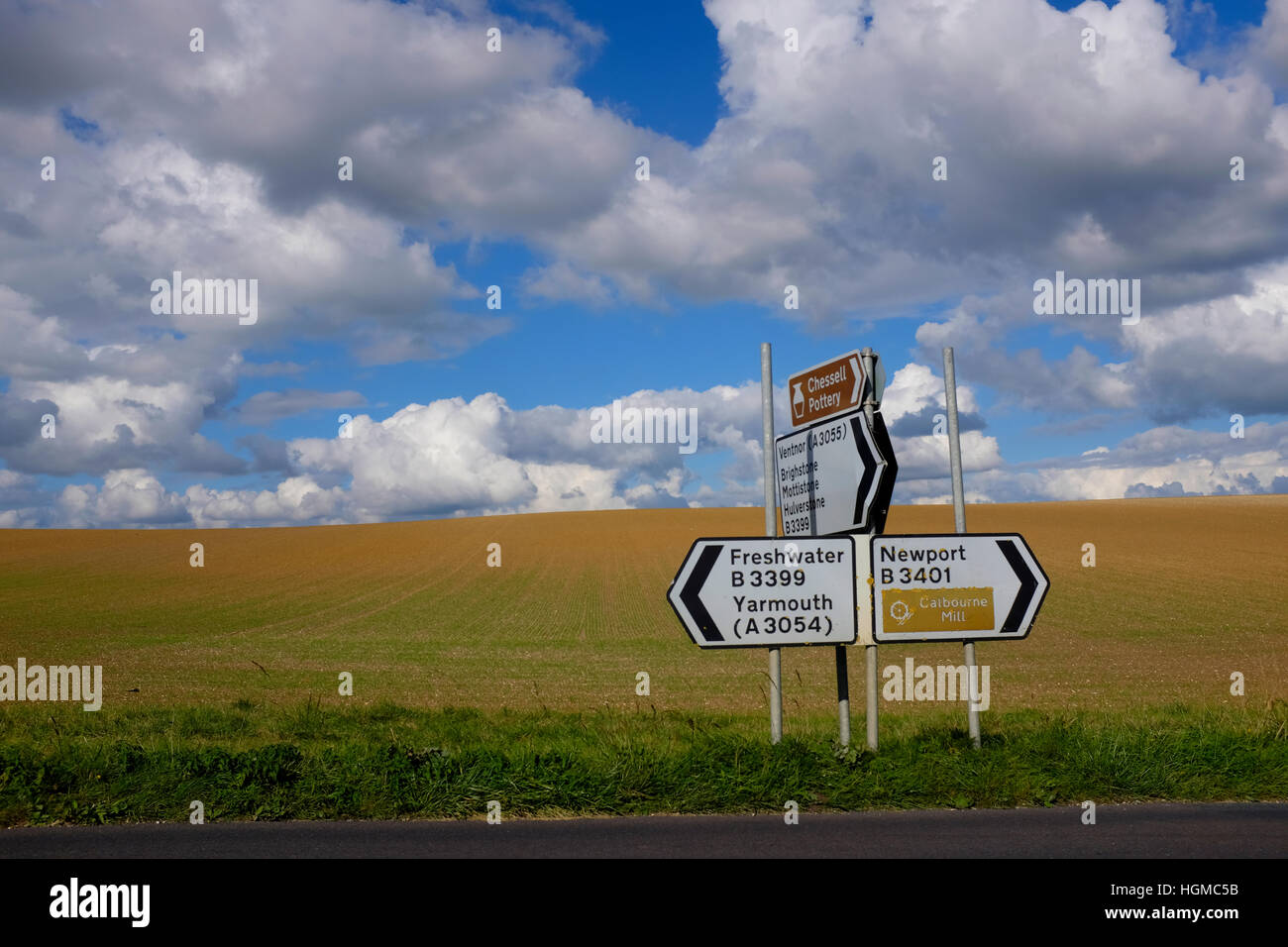 cluster of rural road signs next to farm field wide shot b road clouds ...