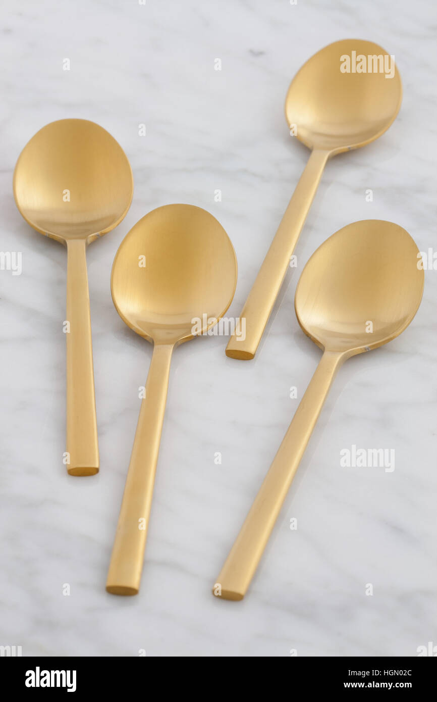 golden spoon set styled on antique carrara marble Stock Photo - Alamy