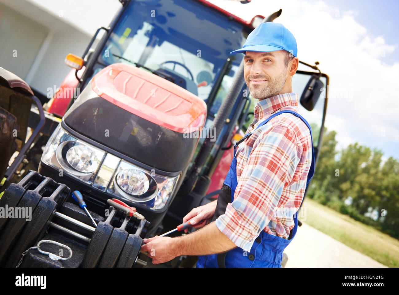 Farmer repairing his big tractor Stock Photo - Alamy