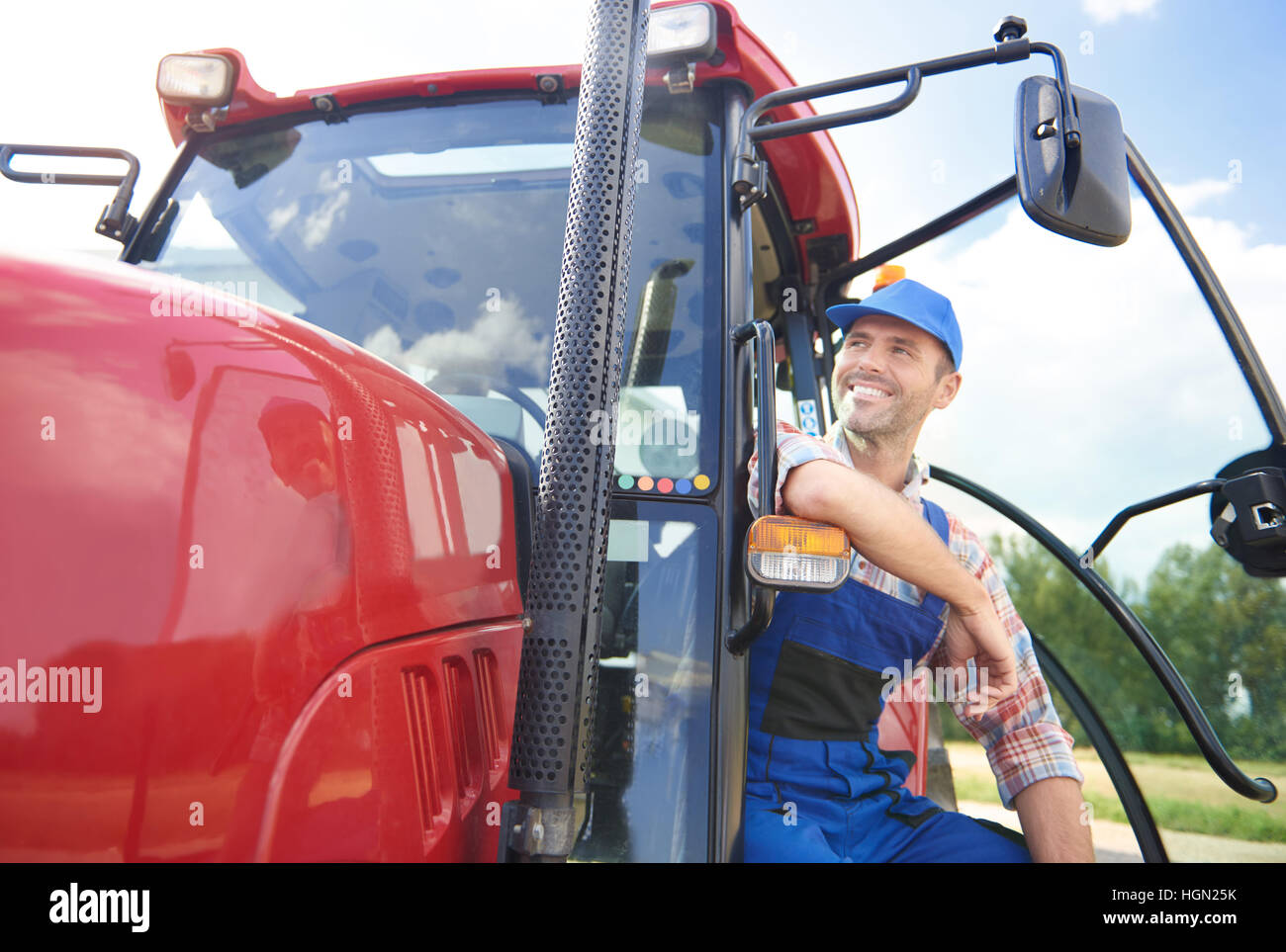 Young farmer sitting on the tractor Stock Photo - Alamy