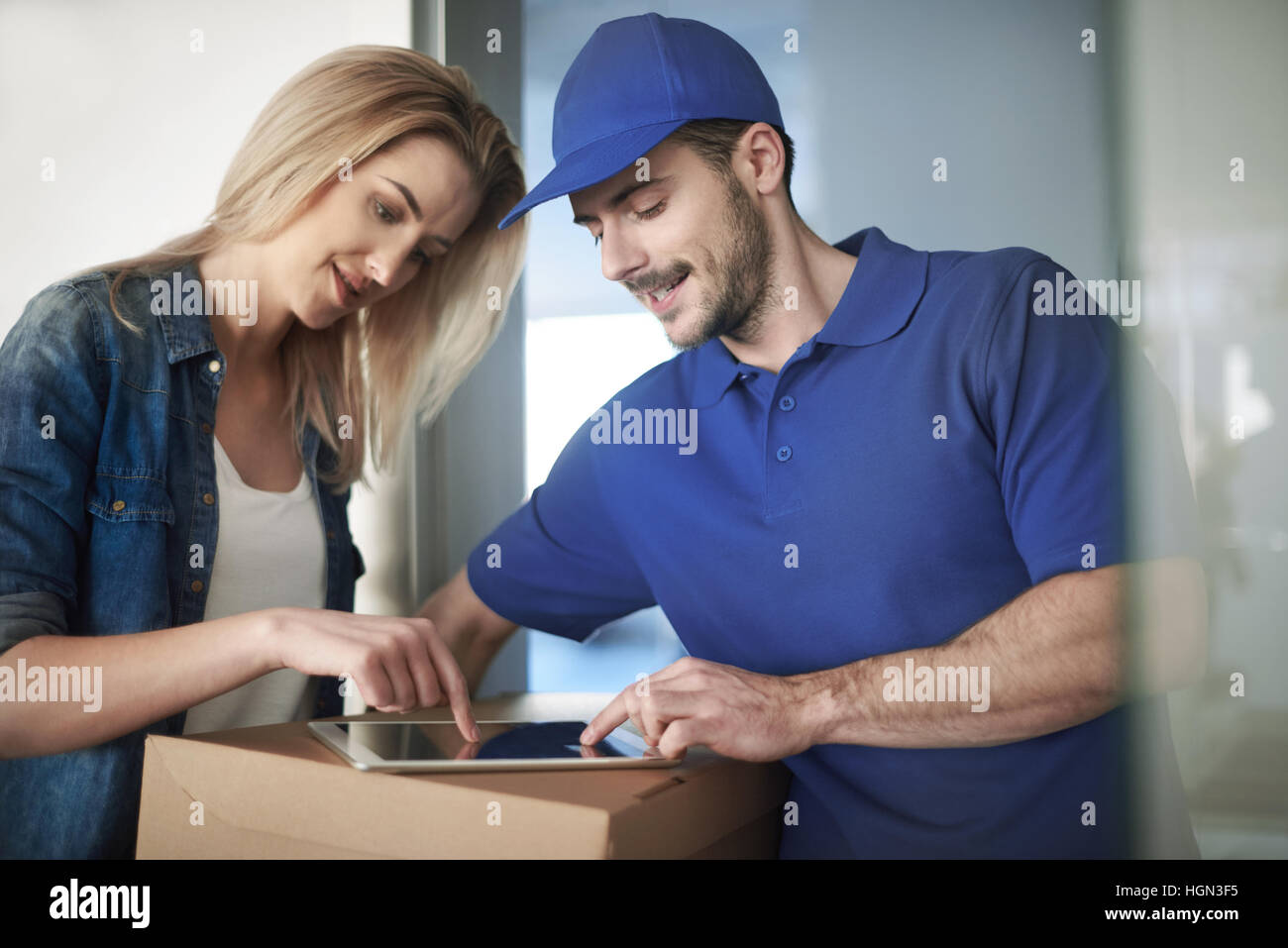 Woman signing package by using digital tablet Stock Photo - Alamy