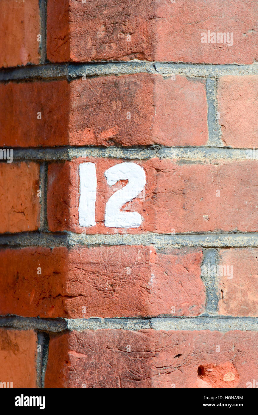 House Number 12 sign painted white on red brick wall Stock Photo - Alamy