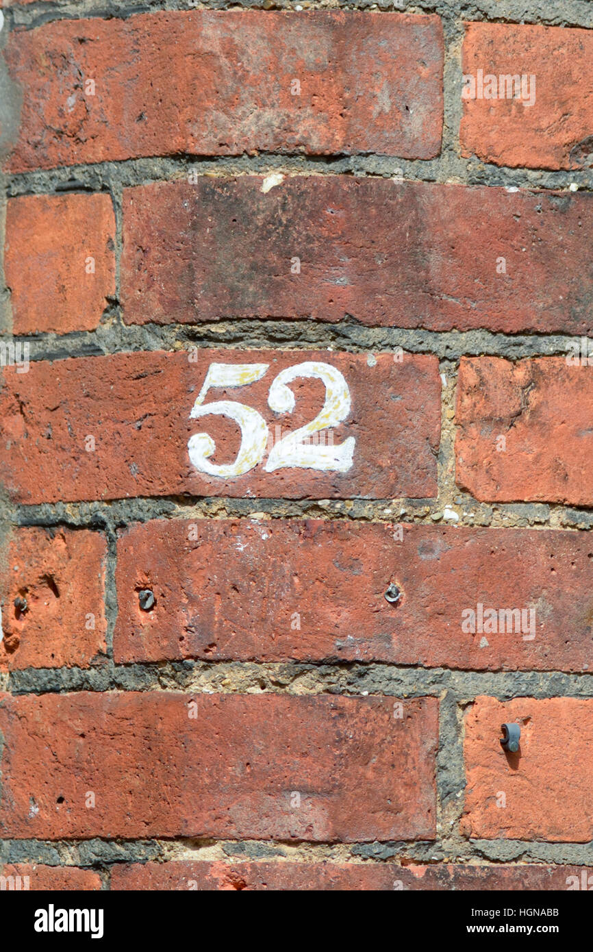 House Number 52 sign on painted white on red brick wall Stock Photo - Alamy