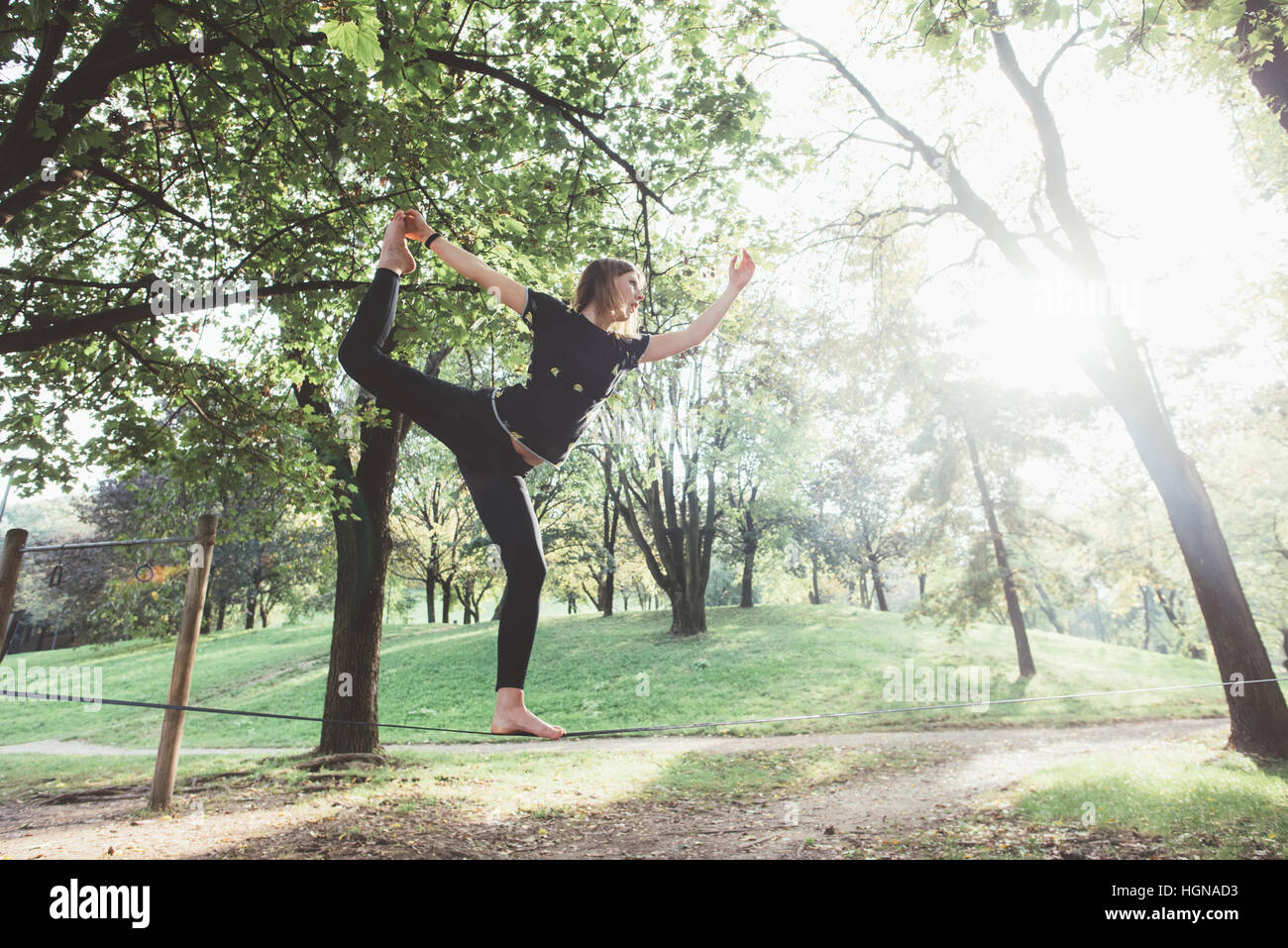 Woman balancing a tightrope or slackline outdoor in a city park in ...