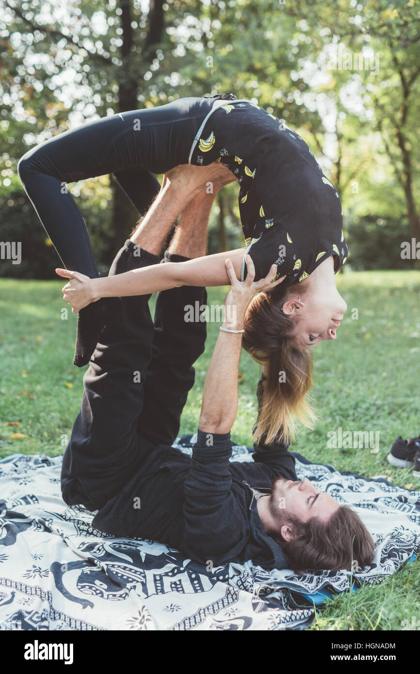 Man lifting up woman with his feet, training outdoor in a park in back ...