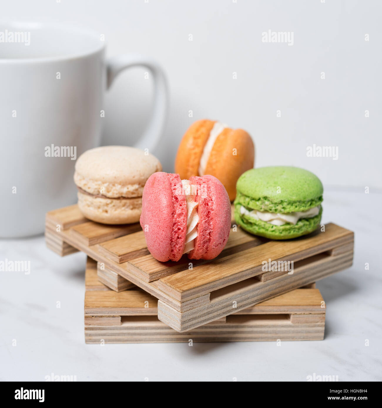 Sweet and colourful macaroons served on little wooden pallets with cup ...