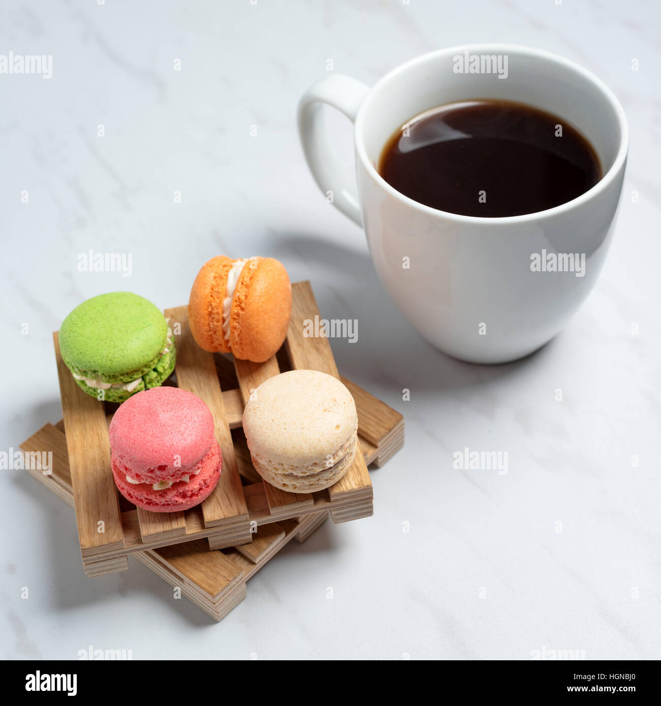 Sweet and colourful macaroons served on little wooden pallets with cup ...