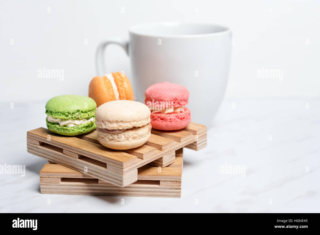 Sweet and colourful macaroons served on little wooden pallets with cup ...