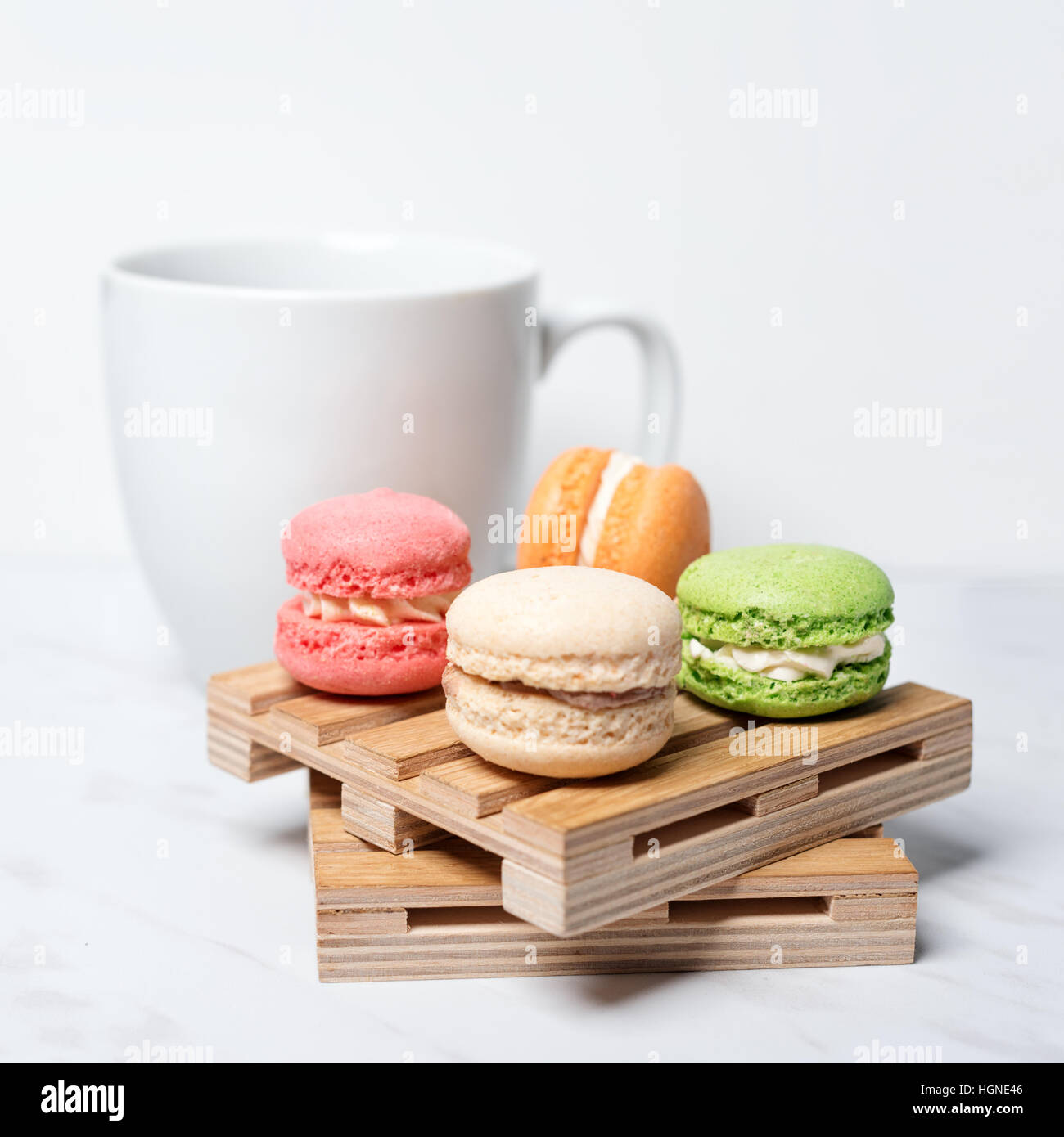 Sweet and colourful macaroons served on little wooden pallets with cup ...