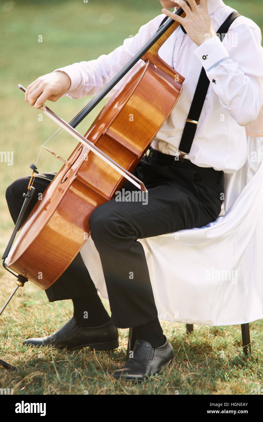 Young man playing cello outside. Cellist playing classical music on ...