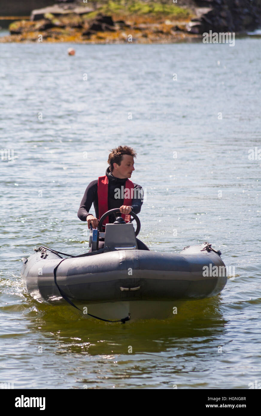 Man in motor dinghy tender outboard at Porthclais harbour near St ...