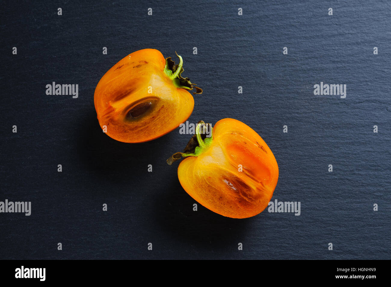 Slices of persimmon on black slate stone background. Top view Stock ...