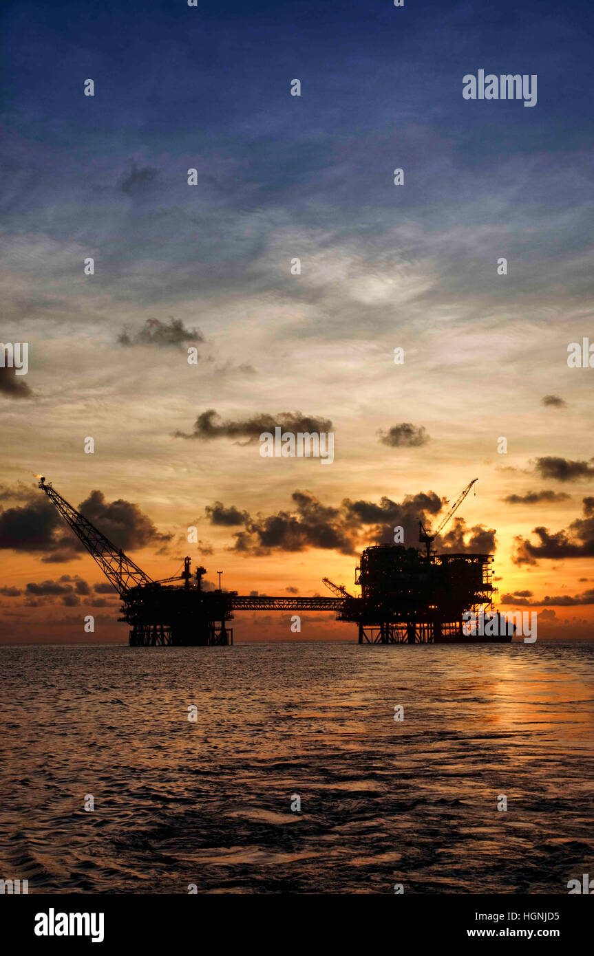 silhouette oil platform during sunset at middle of the sea with clear ...