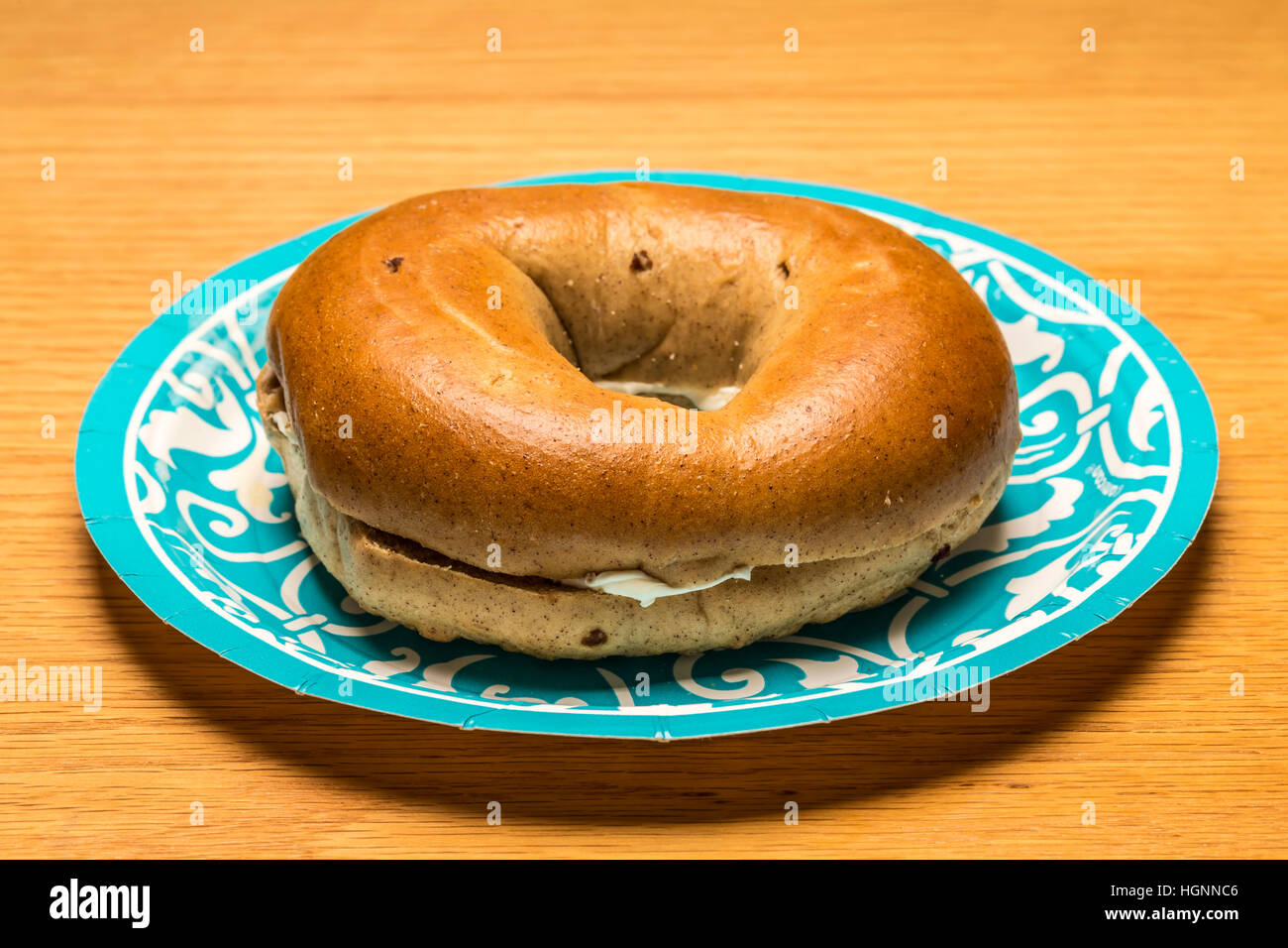 bagel with cream cheese on blue paper plate on wooden table Stock Photo ...