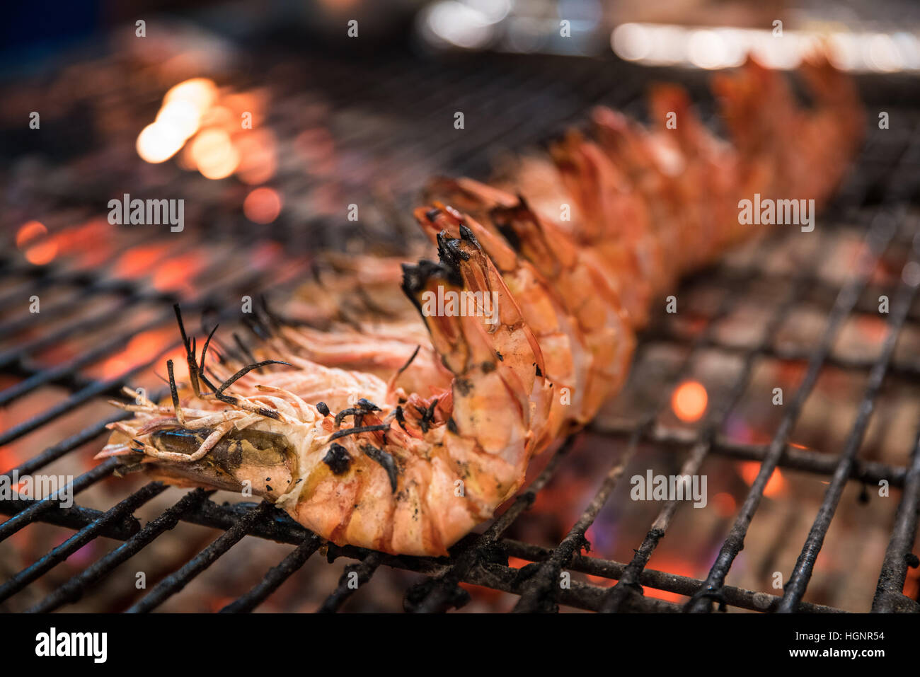 Grilled prawns on flaming grill show in front of restaurant at night ...