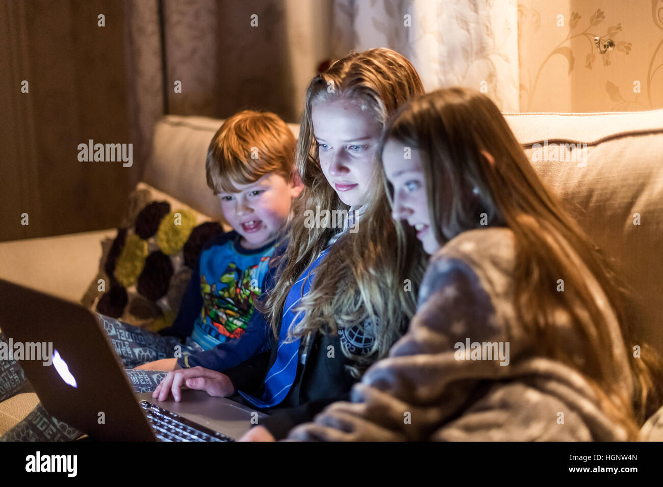 Children sat at home looking at a computer laughing at a TV show Stock ...