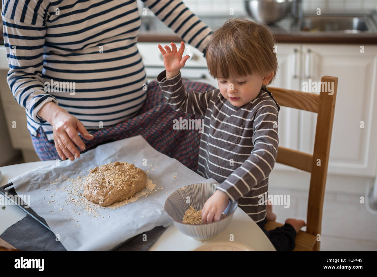 Pregnant mom and making bread in the kitchen with her son Toddler ...