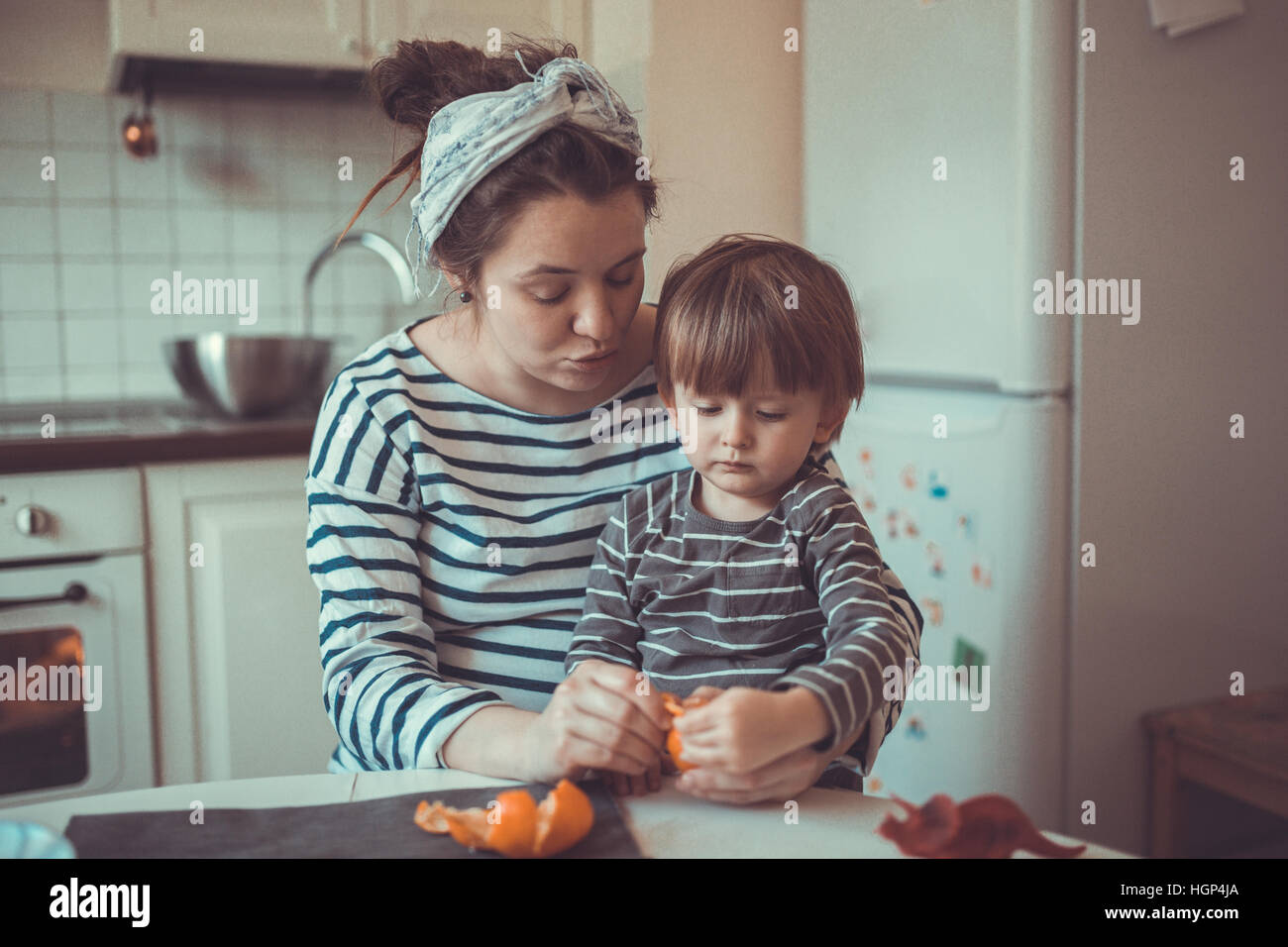 happy mother and son Toddler at the kitchen table eating tangerines ...