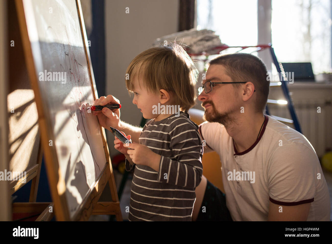 Dad and son together paint on Easel. Real interior, toning soft focus ...
